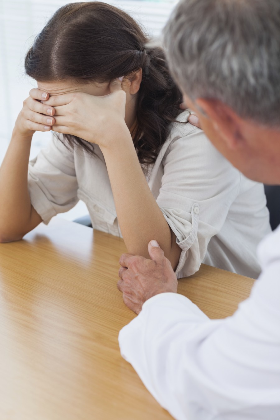 Upset patient crying while doctor comforting her in bright surgery ...